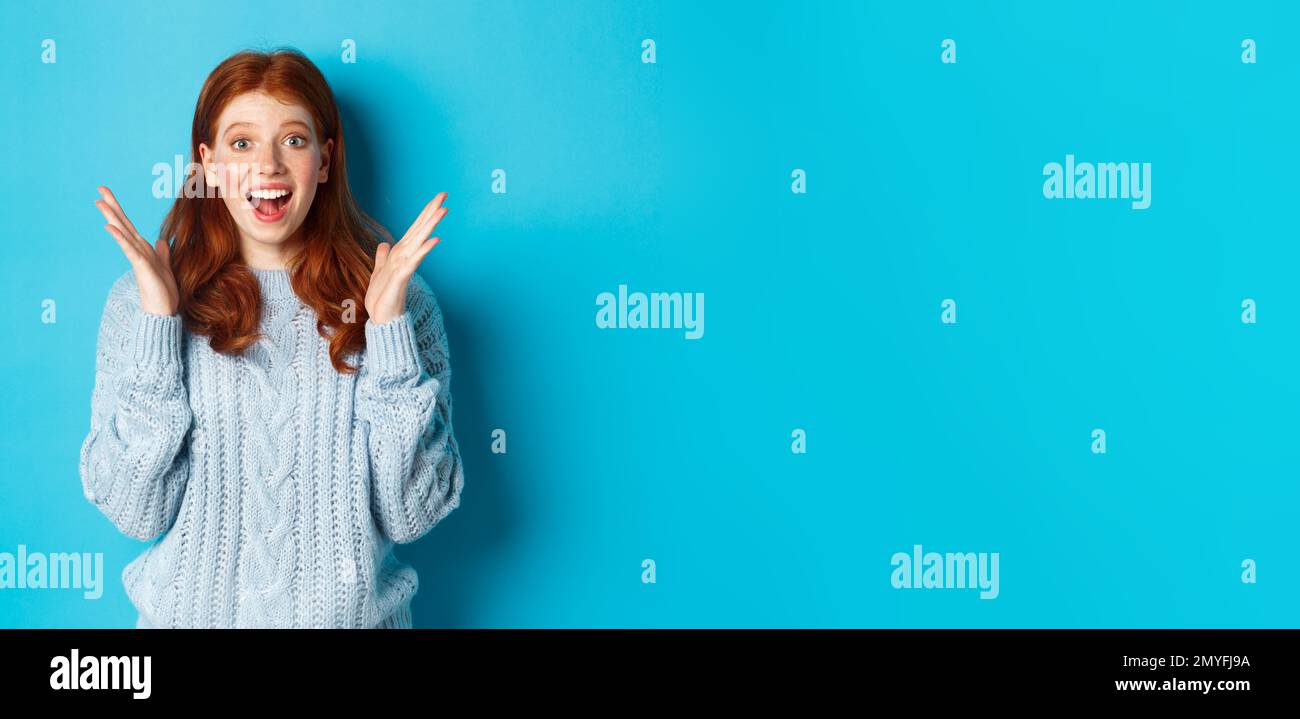 Surprised and happy redhead girl clap hands and staring at camera ...