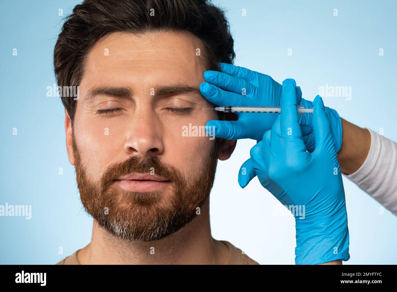 Handsome middle aged bearded man getting under eye injections in beauty ...