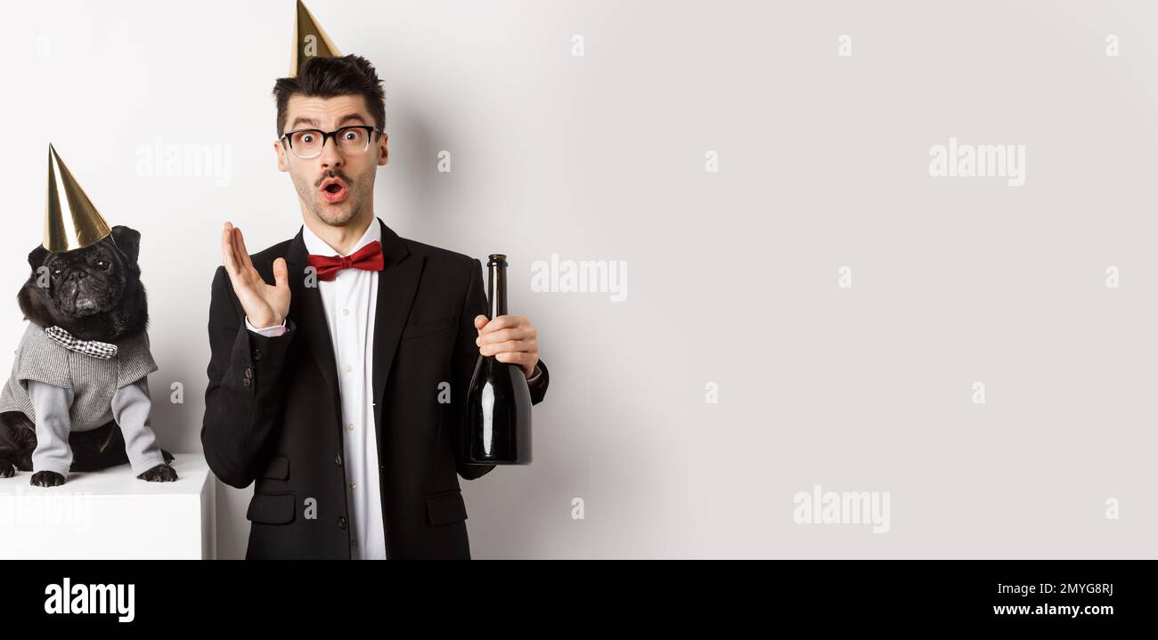 Happy young man celebrating holiday with cute dog, holding champagne ...
