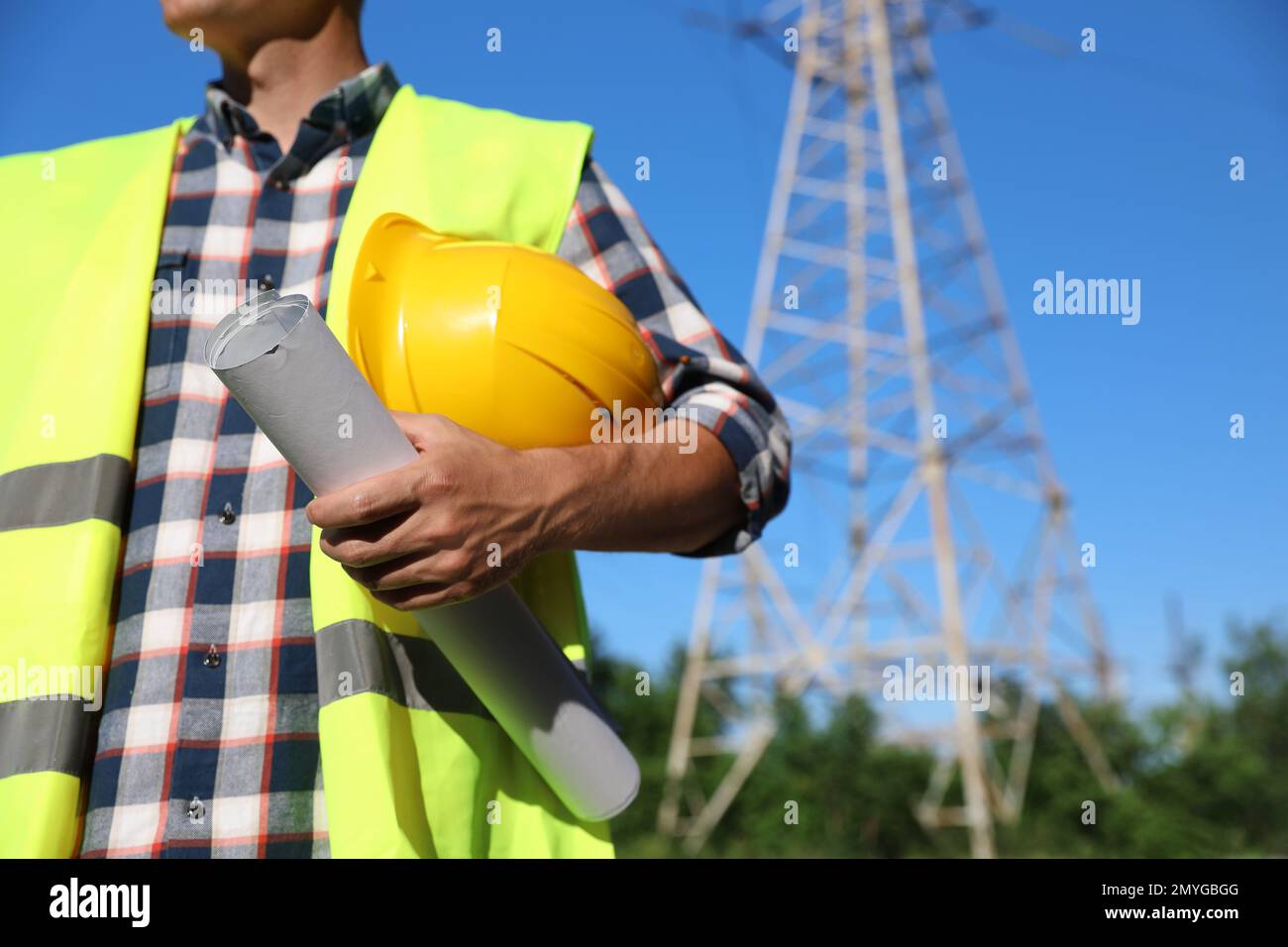 Professional electrician with drafting and helmet near high voltage ...