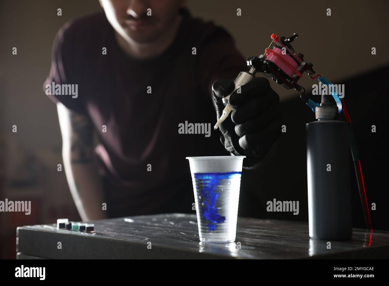 Tattoo artist cleaning machine needle at table, closeup Stock Photo - Alamy