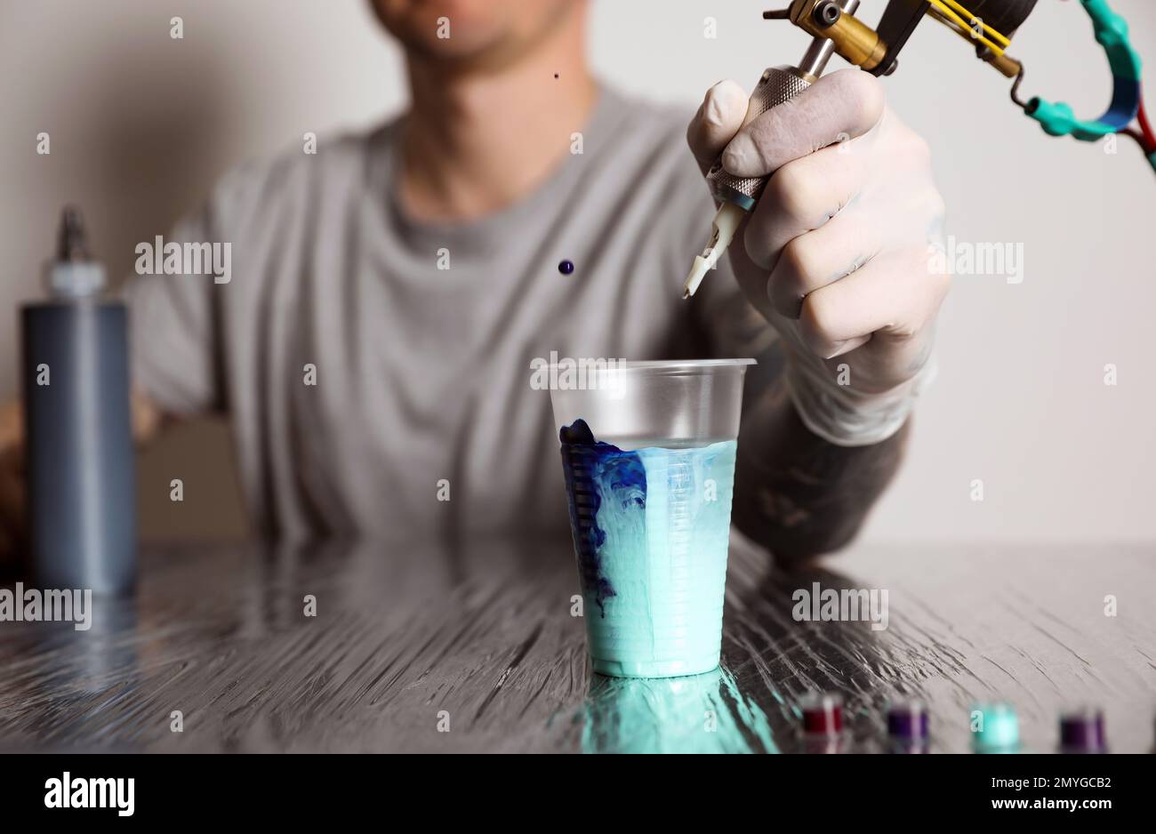 Tattoo artist cleaning machine needle at table, closeup Stock Photo - Alamy
