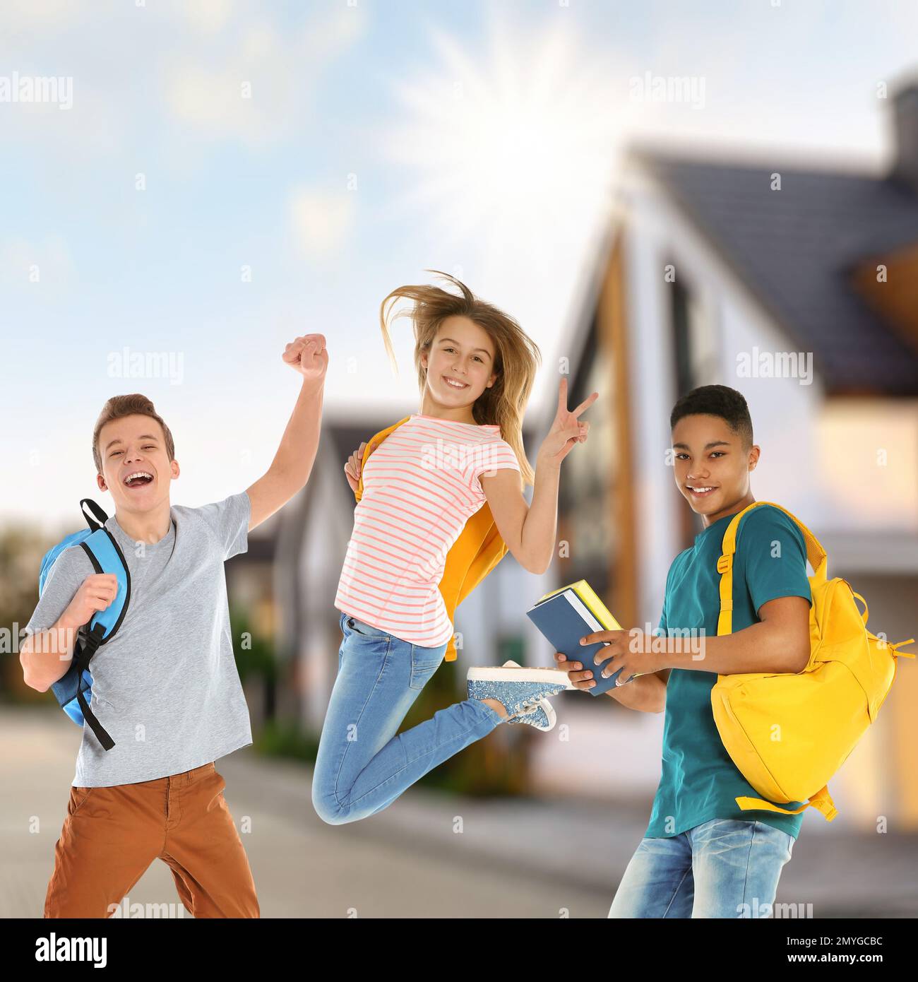 Happy teenage girl jumping near classmates in front of house. School ...