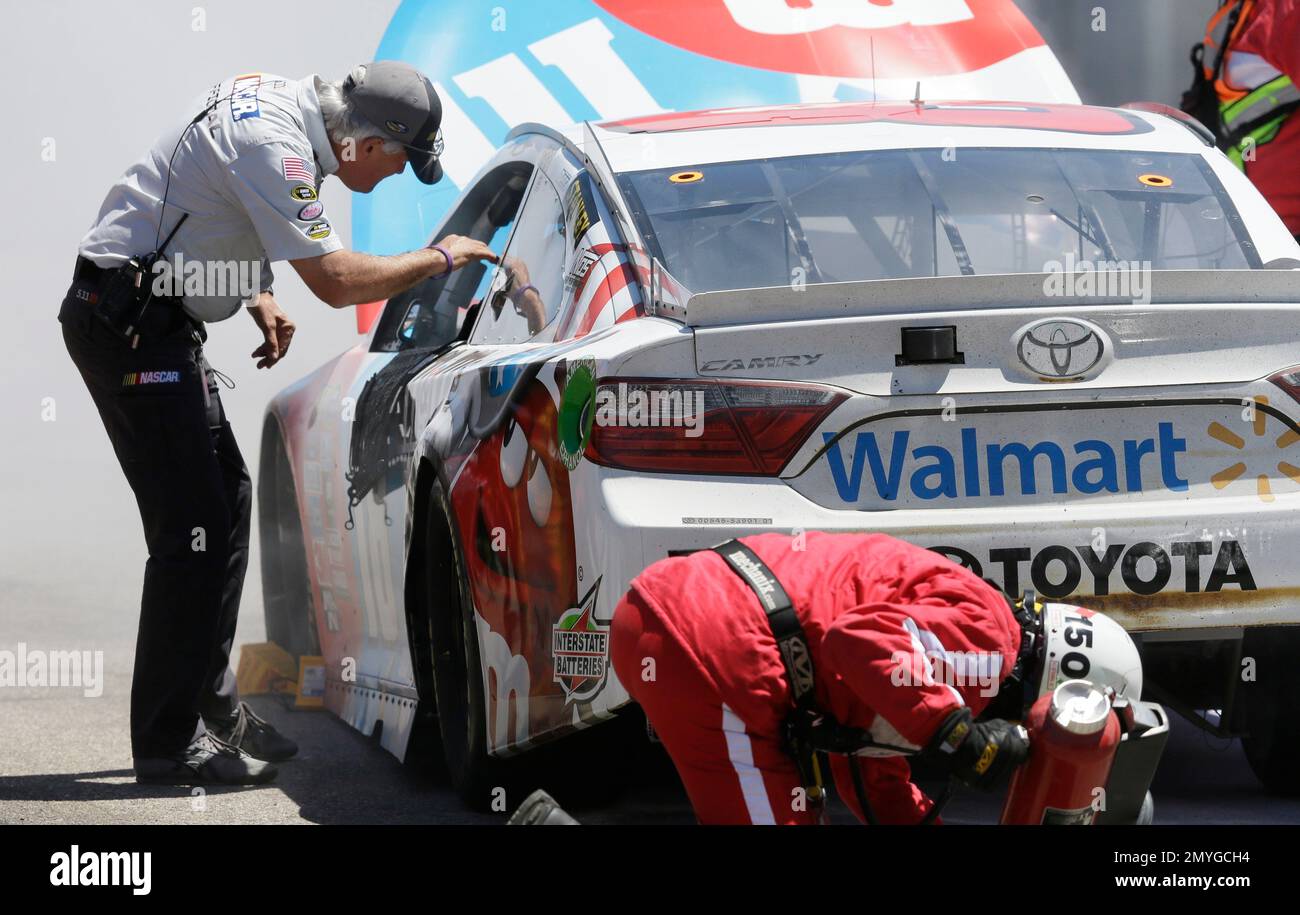 A race car official checks with driver Kyle Busch as safety crews put ...