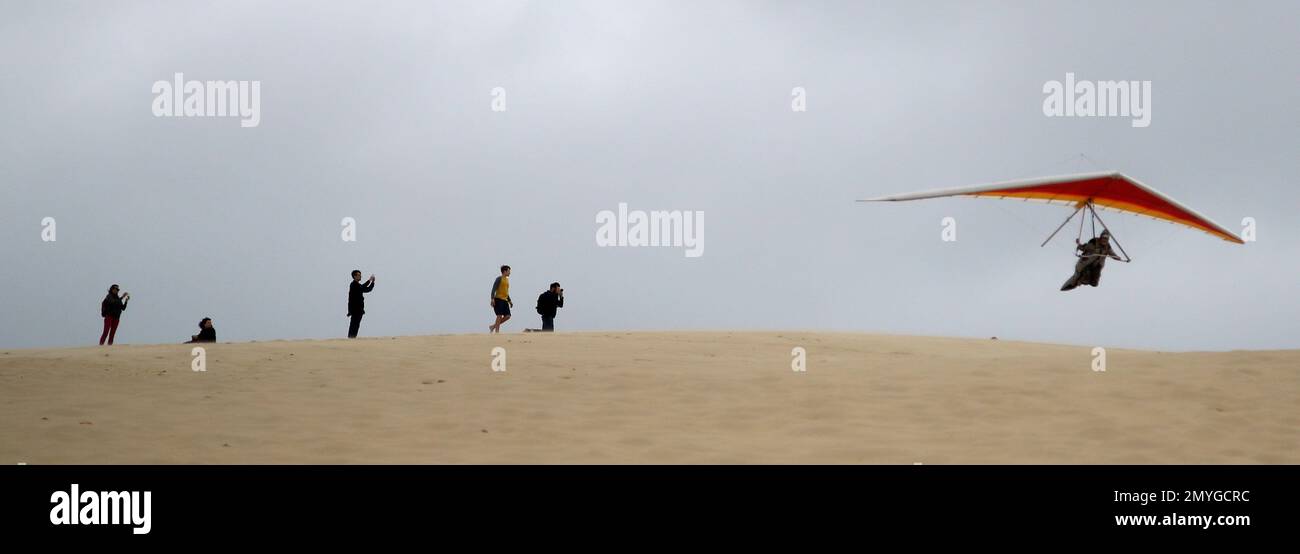 A hang glider takes off from the Great Dune of Pyla near the town of ...