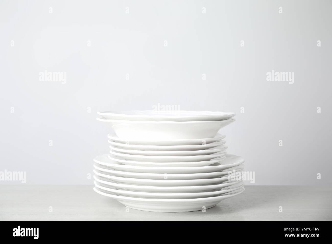 Stack of clean plates on table against white background. Space for text ...