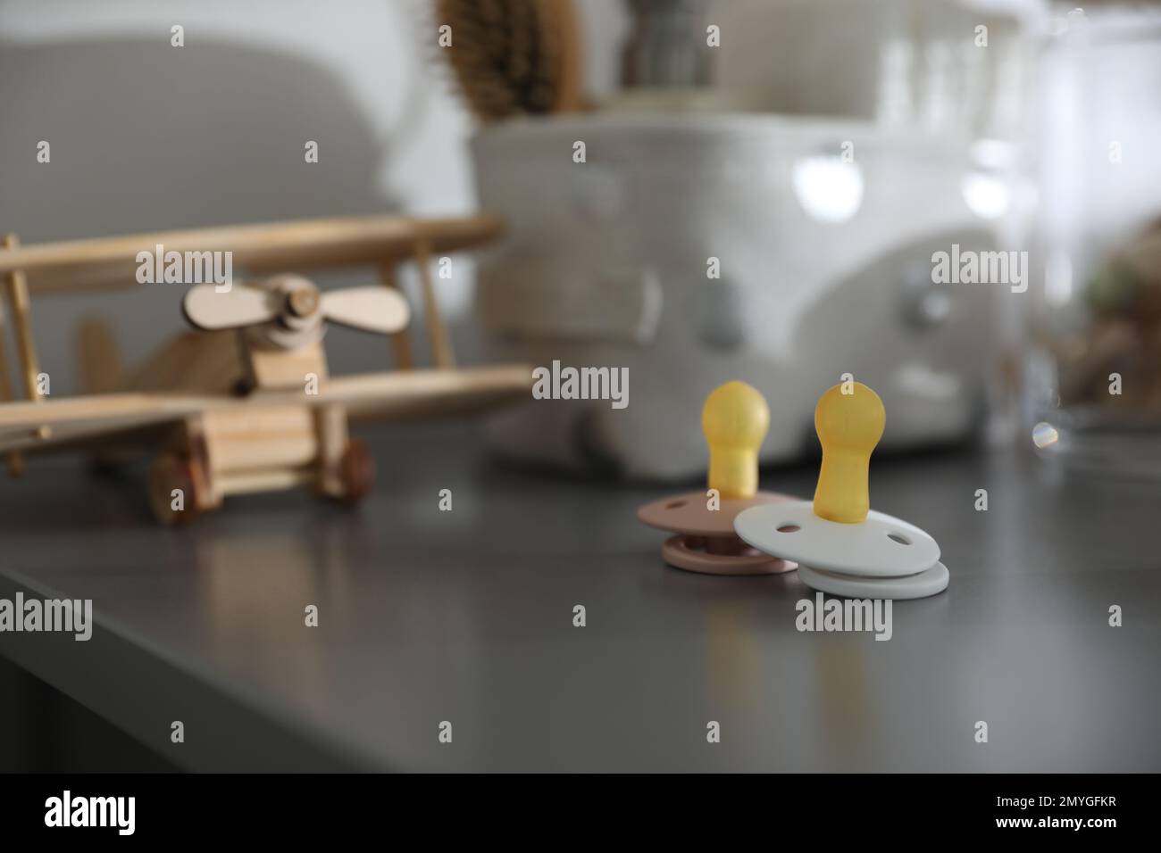 Pacifiers on grey table in child room, space for text Stock Photo - Alamy