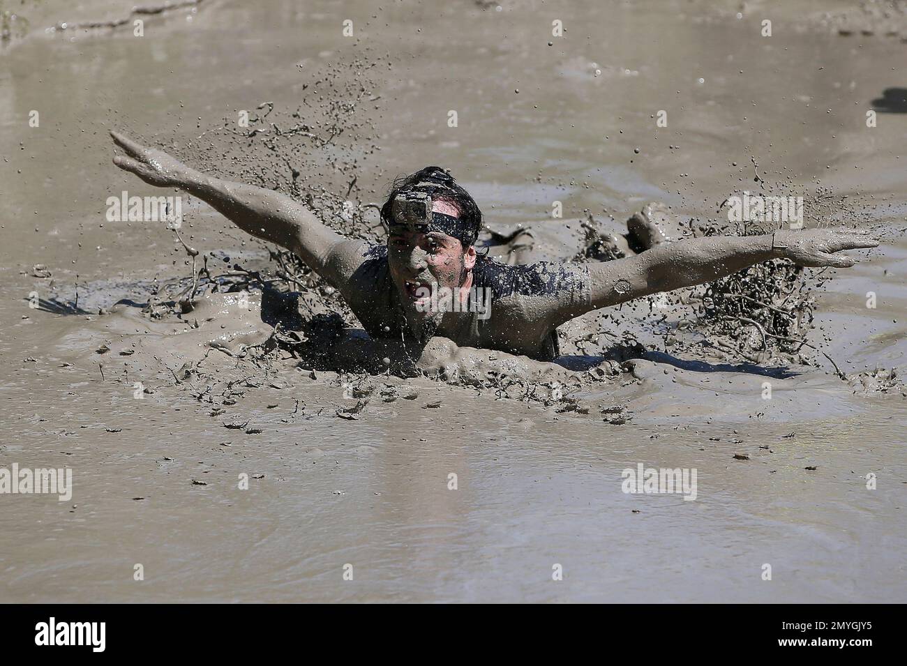 A participant swims to cross a mud pool during the Mud Day athletic ...