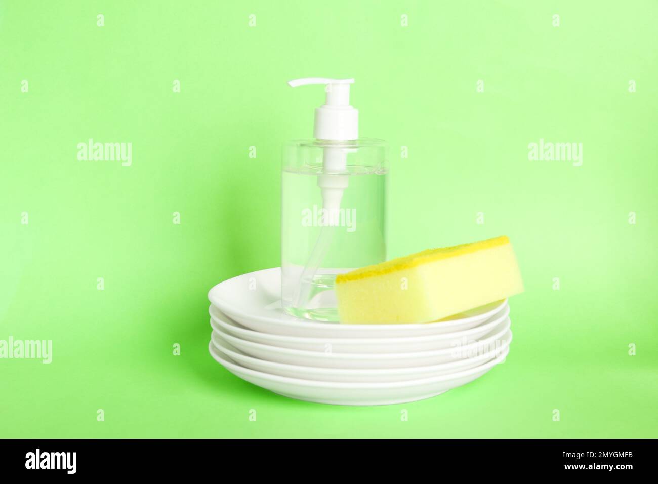 Detergent, plates and sponge on green background. Clean dishes Stock ...