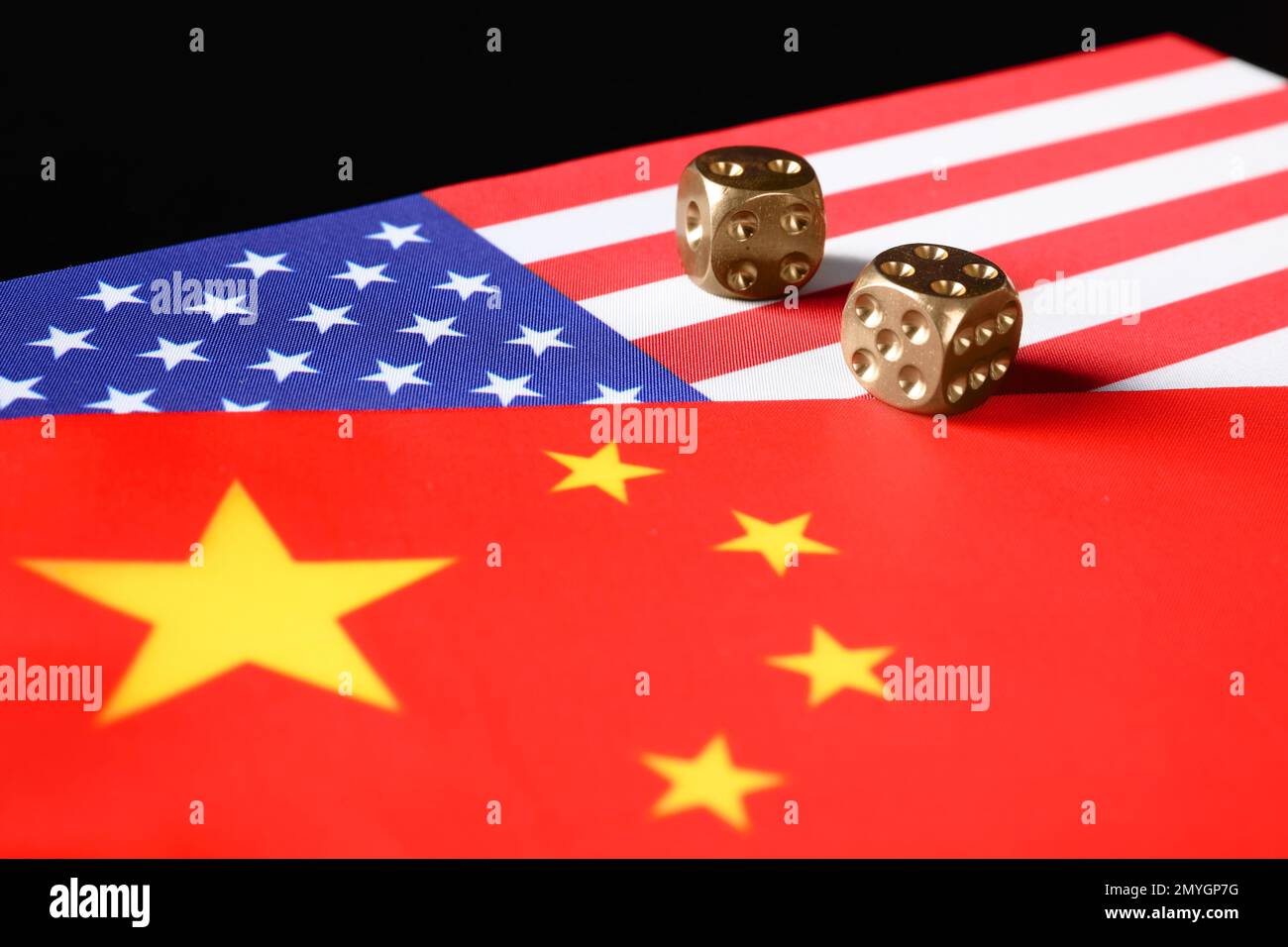 USA and China flags with dice on black table. International relations ...