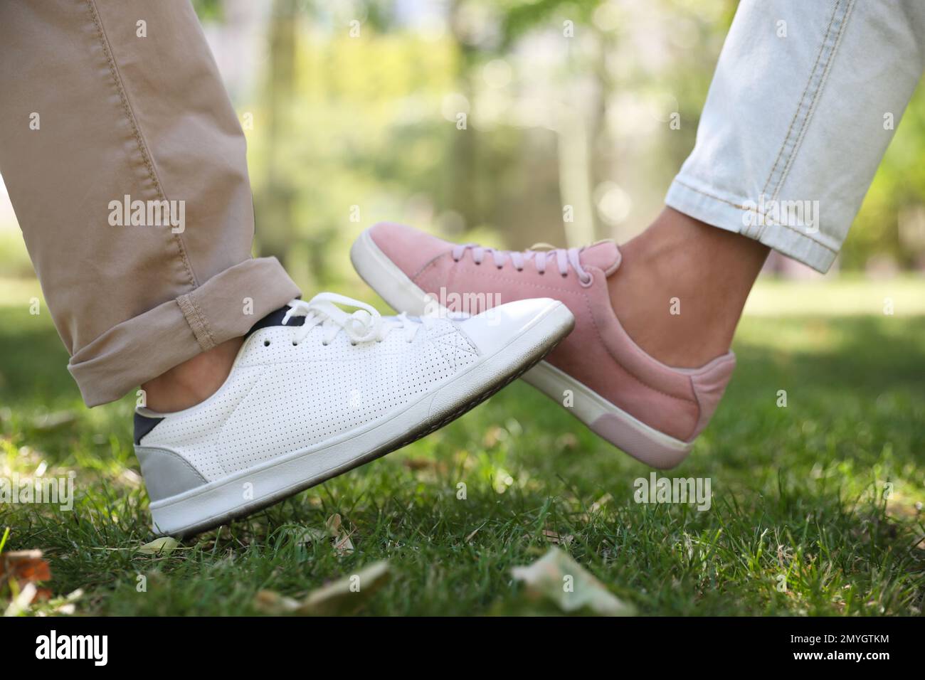 Man and woman bumping legs to say hello outdoors, closeup. Keeping ...