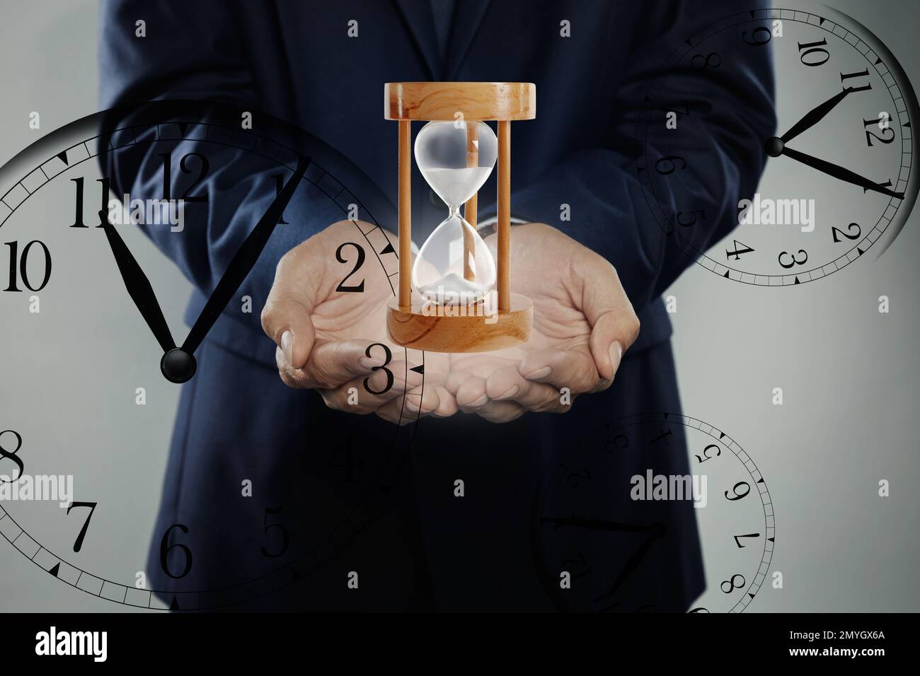 Time management concept. Man with hourglass surrounded by clocks ...