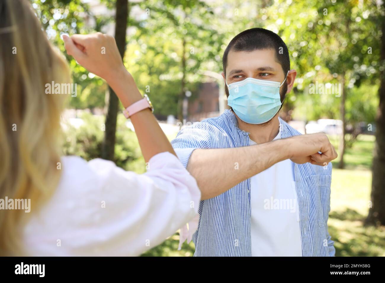 Man and woman bumping elbows to say hello outdoors. Keeping social ...