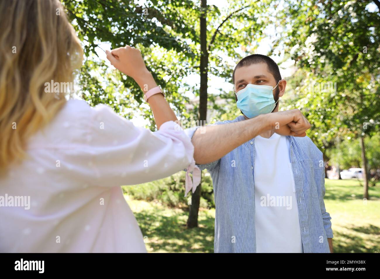 Man and woman bumping elbows to say hello outdoors. Keeping social ...