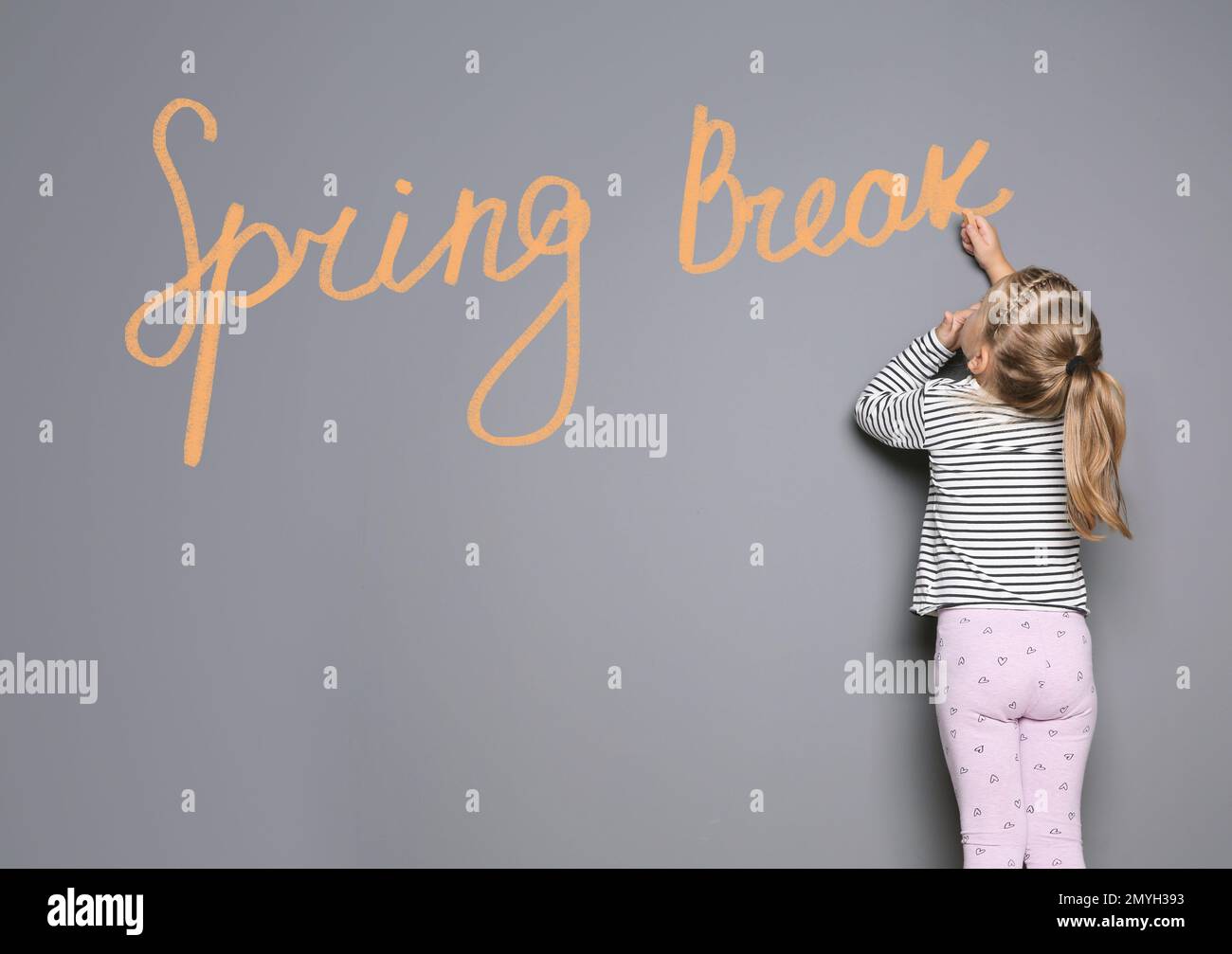 Small girl writing phrase Spring Break with chalk on grey wall. School ...