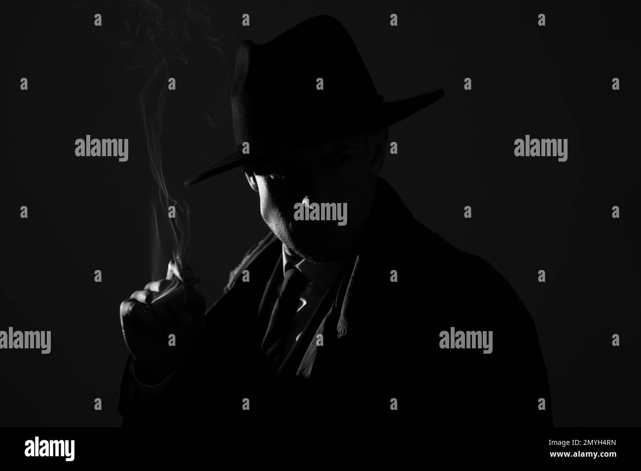 Old fashioned detective smoking cigarette on dark background, black and ...