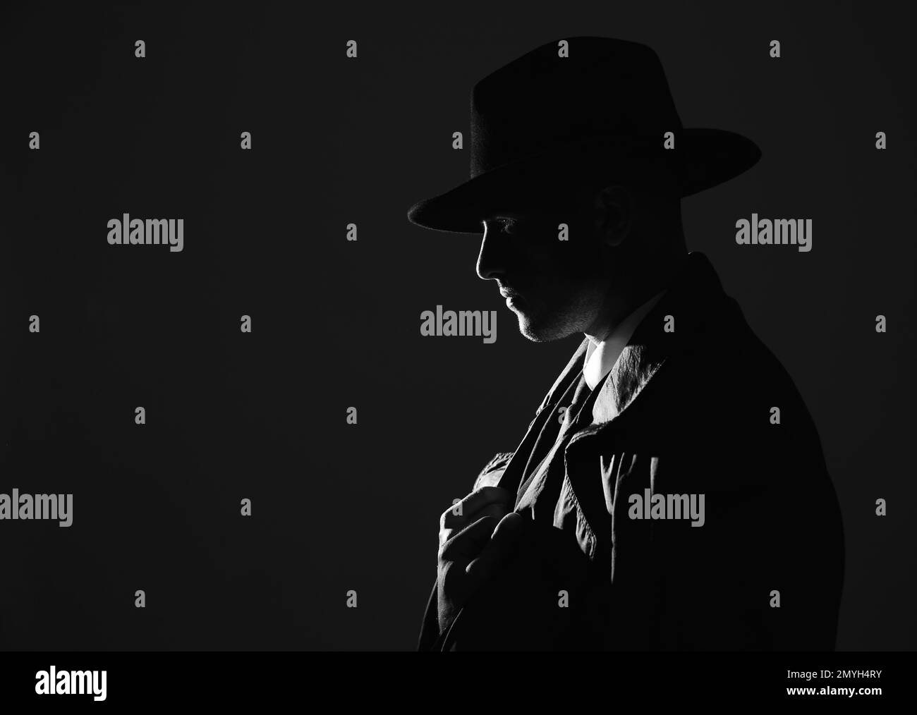 Old fashioned detective in hat on dark background, black and white ...