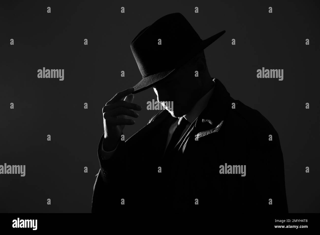Old fashioned detective in hat on dark background, black and white ...