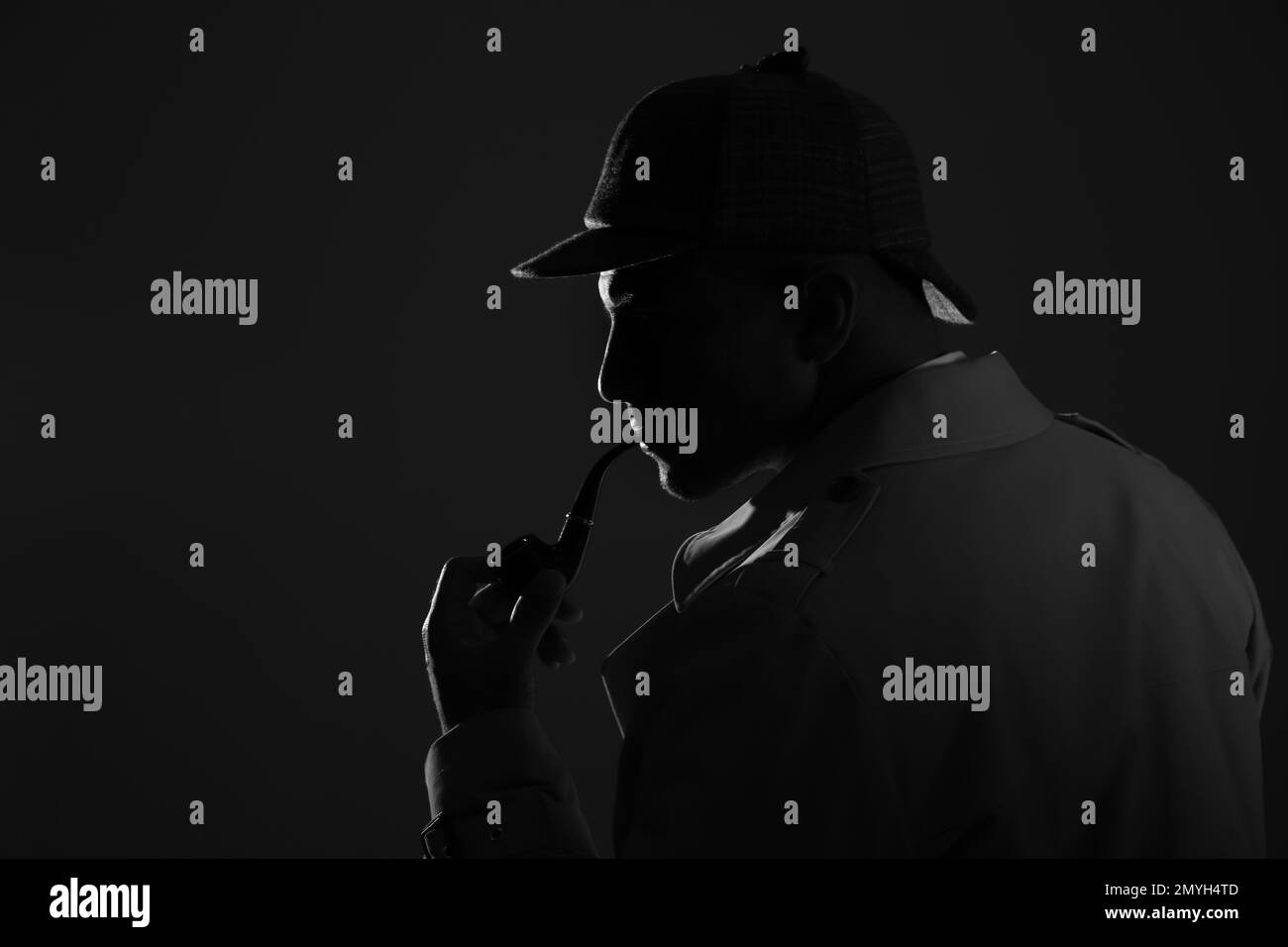 Old fashioned detective with smoking pipe on dark background, black and ...