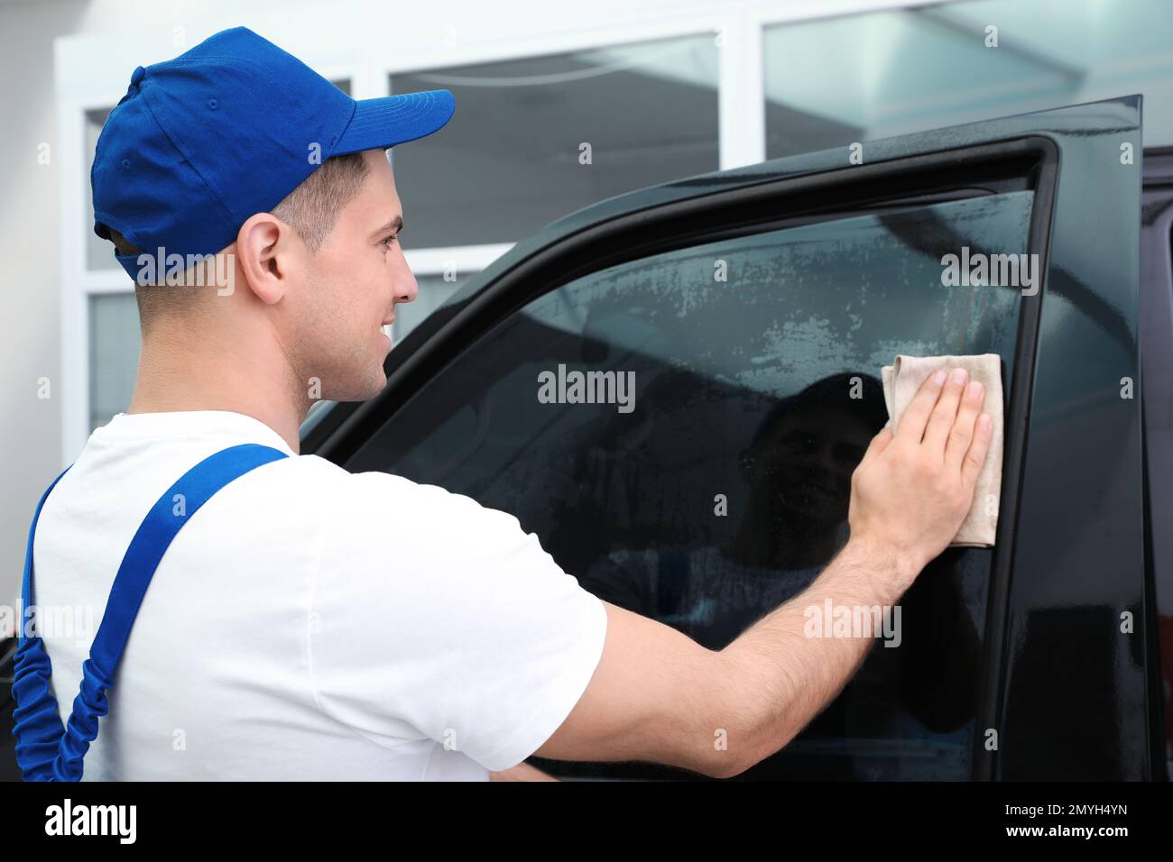 Worker washing tinted car window in workshop Stock Photo - Alamy