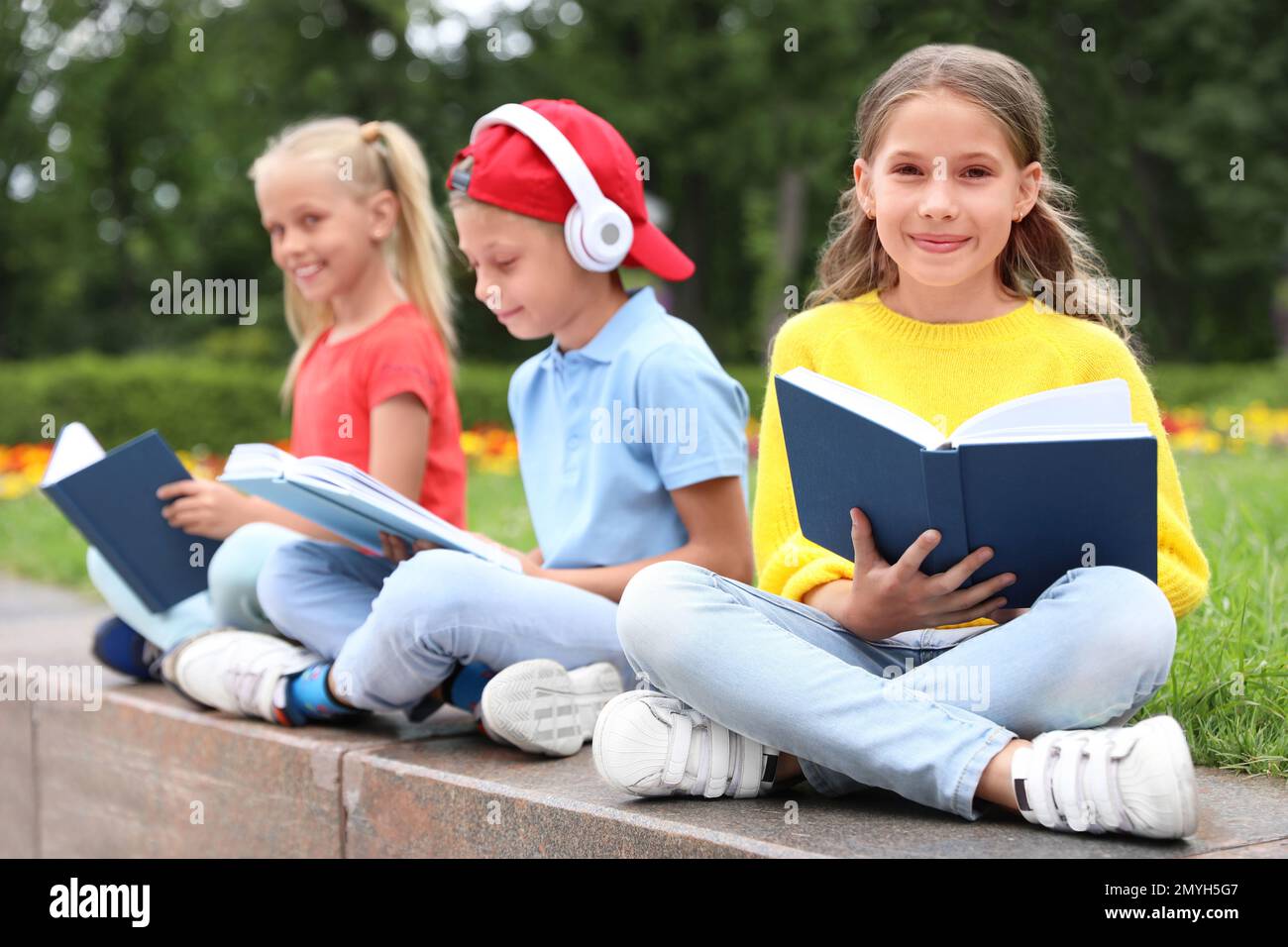 Group of kids reading books on street Stock Photo - Alamy