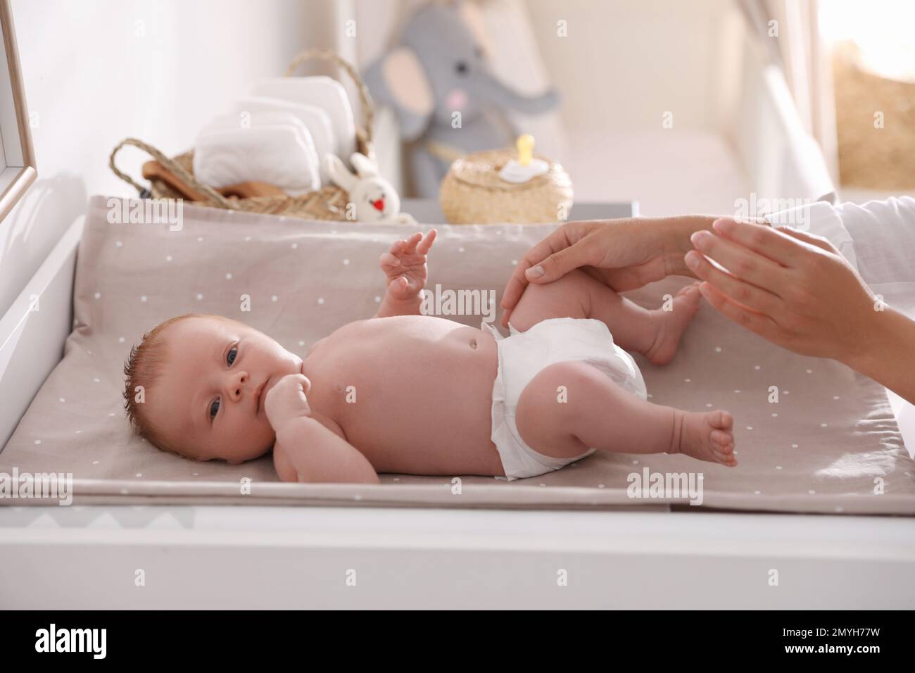 Mother changing her baby's diaper on table in room Stock Photo - Alamy