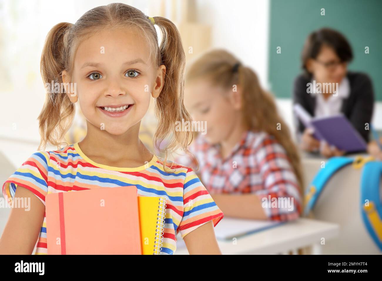 Happy girl with notebooks in school classroom Stock Photo - Alamy