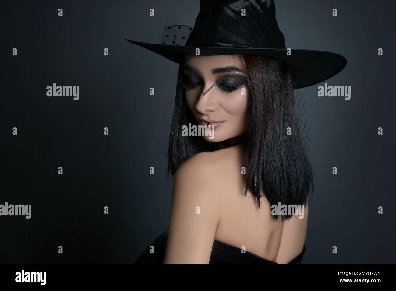 Mysterious witch wearing hat on black background Stock Photo - Alamy