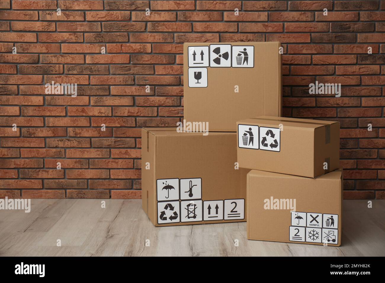 Cardboard boxes with different packaging symbols on floor near brick ...