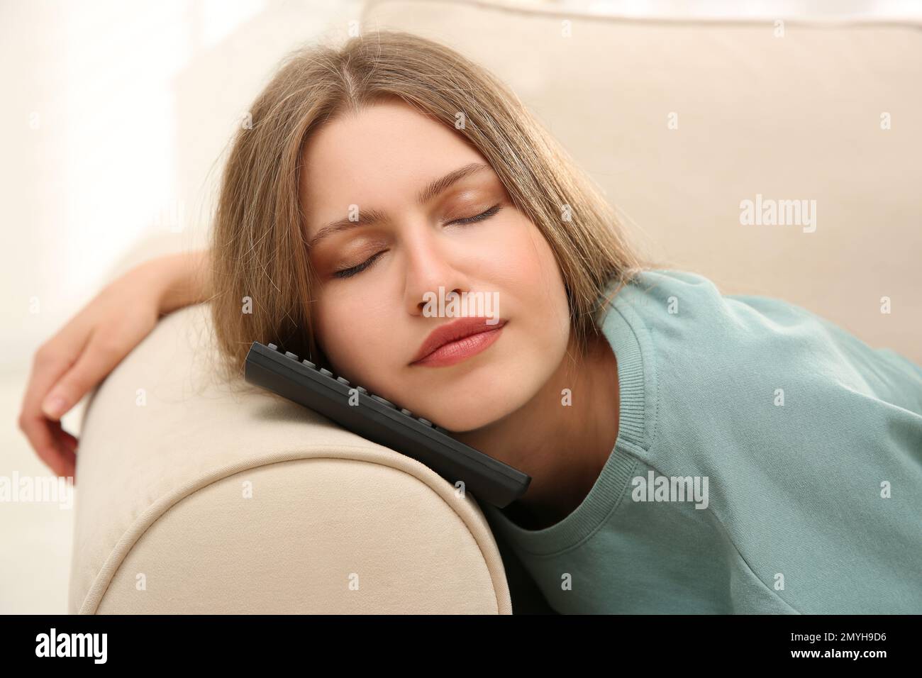 Lazy young woman sleeping on TV remote at home Stock Photo - Alamy