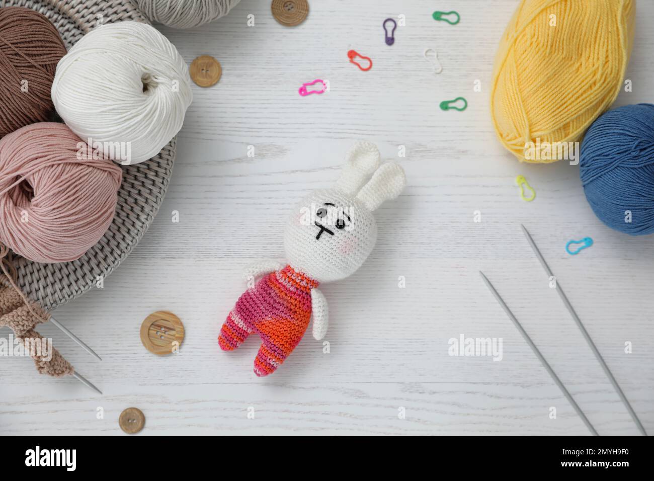 Crocheted bunny and knitting supplies on white wooden table, flat lay ...