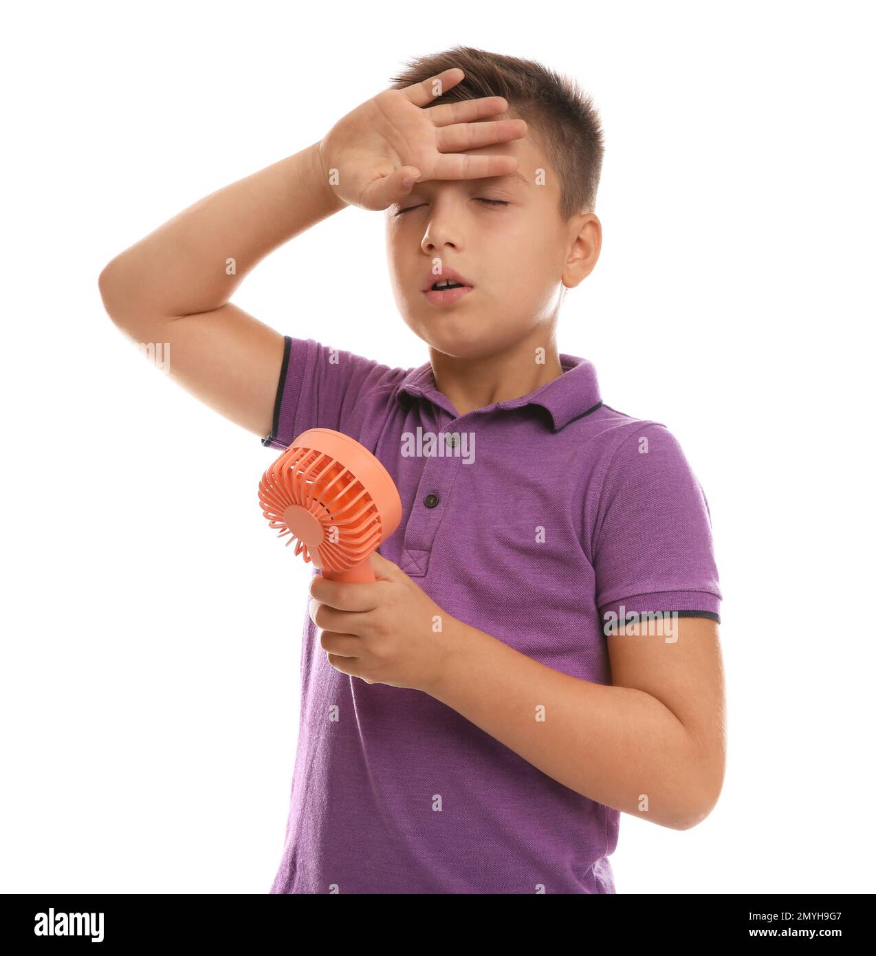 Little boy with portable fan suffering from heat on white background ...