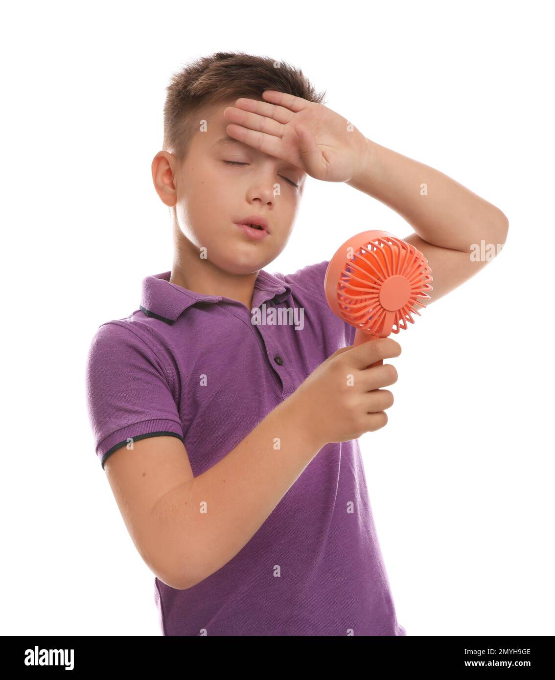 Little boy with portable fan suffering from heat on white background ...