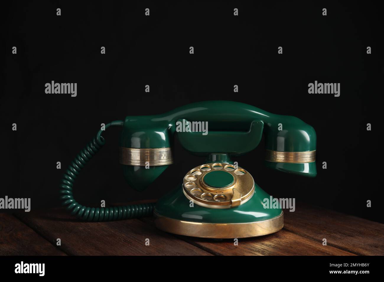 Vintage corded phone on wooden table against black background Stock ...