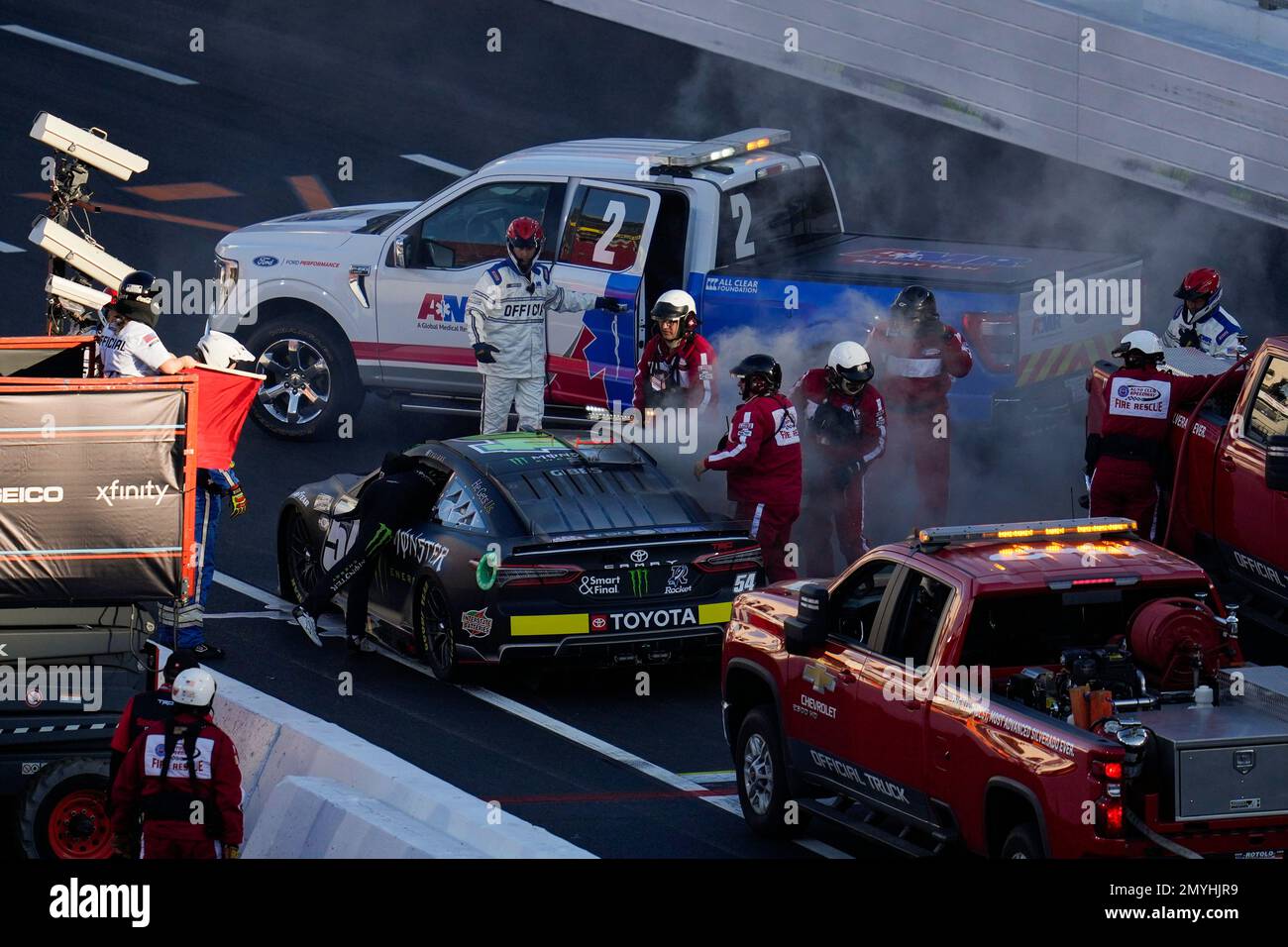 Emergency crews extinguish flames after a car driven by NASCAR Cup ...