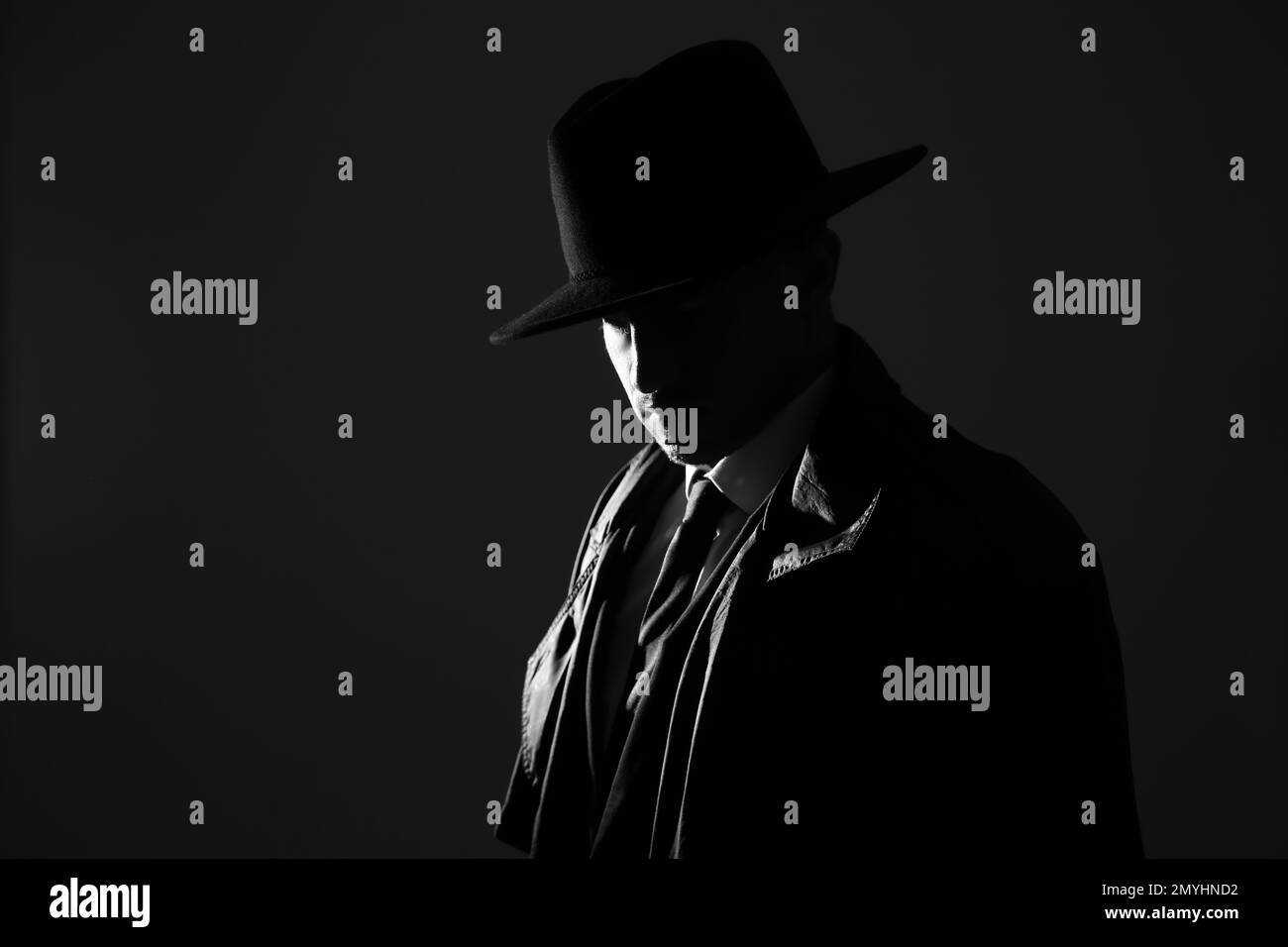 Old fashioned detective in hat on dark background, black and white ...