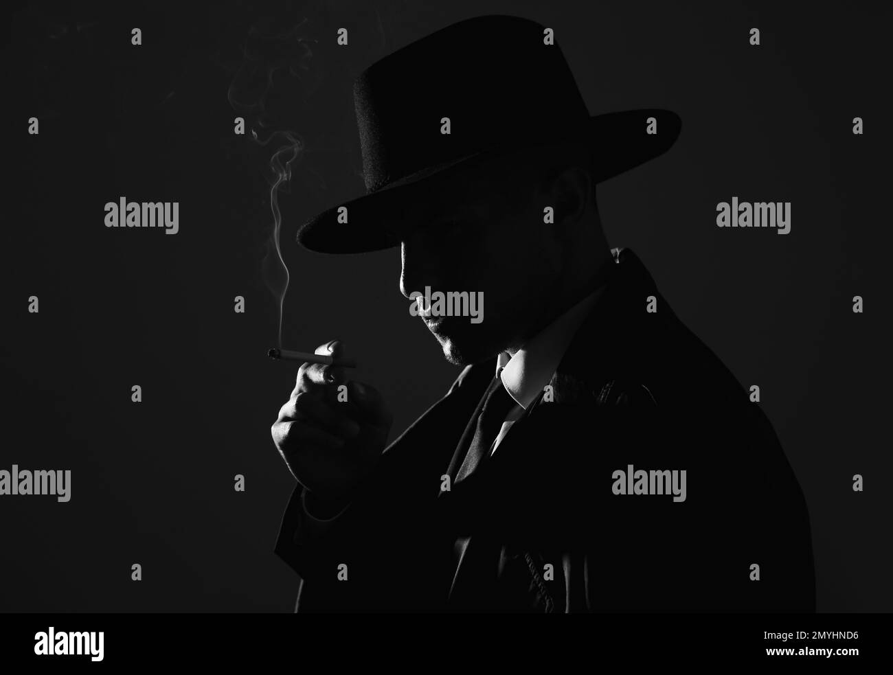 Old fashioned detective smoking cigarette on dark background, black and ...