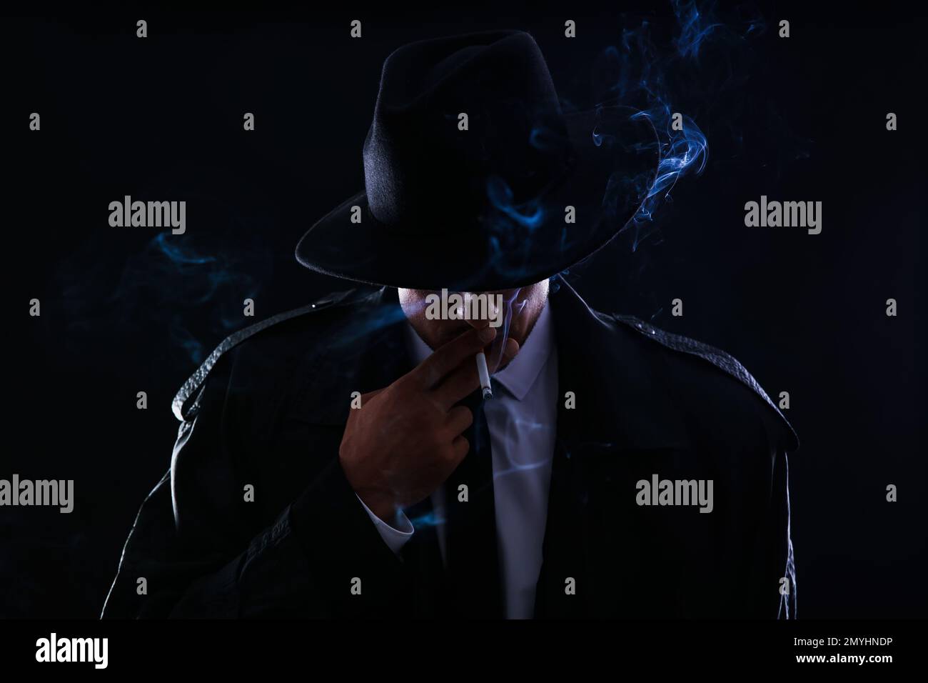 Old fashioned detective smoking cigarette on dark background Stock ...