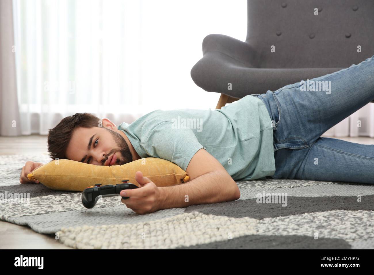 Lazy young man playing video game while lying on floor at home Stock ...