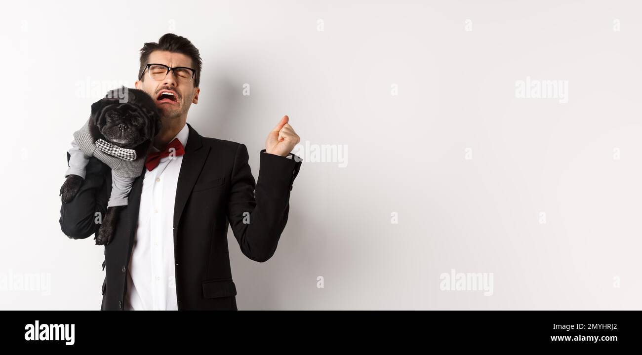 Sad man in suit, holding cute small dog on shoulder and crying with ...