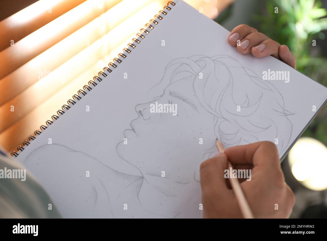 Man drawing portrait with pencil in notepad indoors, closeup Stock ...