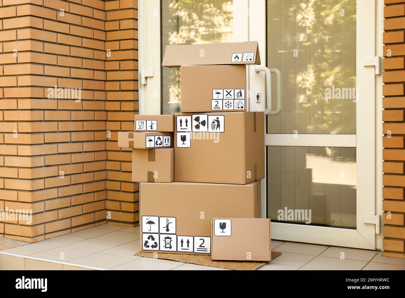 Cardboard boxes with different packaging symbols on door mat near ...