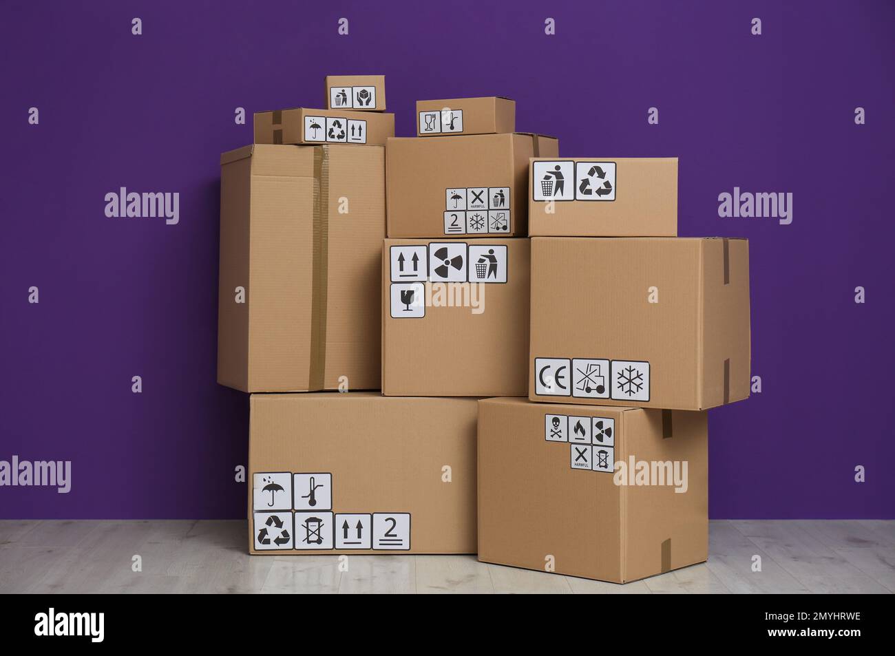 Cardboard boxes with different packaging symbols on floor near purple ...