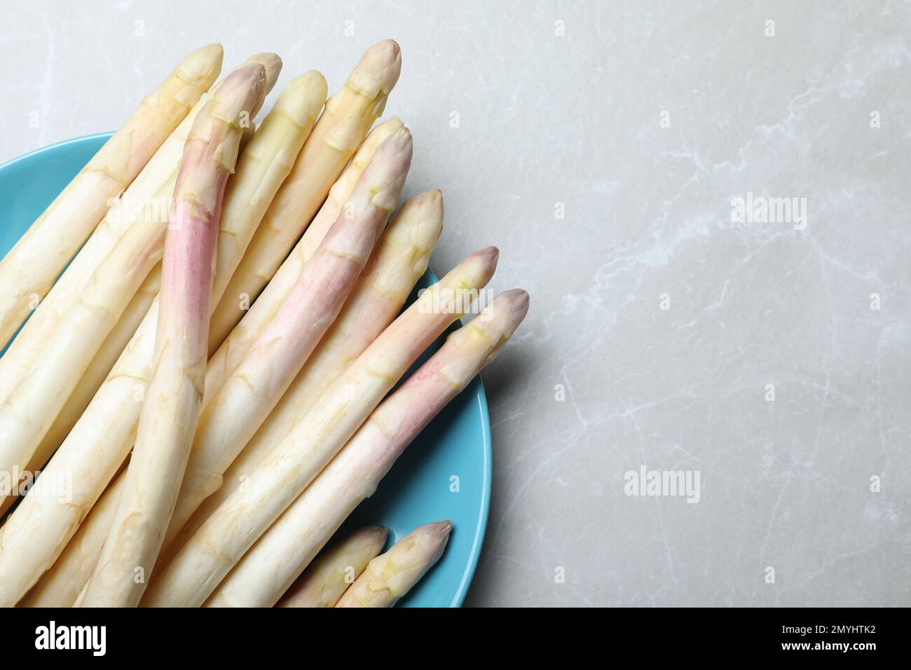 Fresh white asparagus on grey marble table, top view. Space for text ...