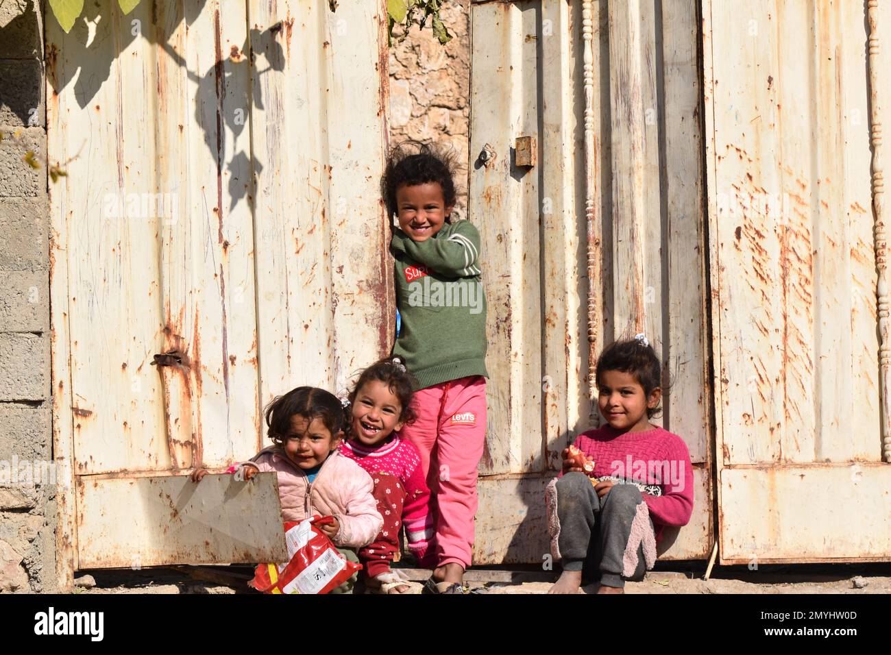 Four little girls playing outside smile at strangers walking past Stock ...
