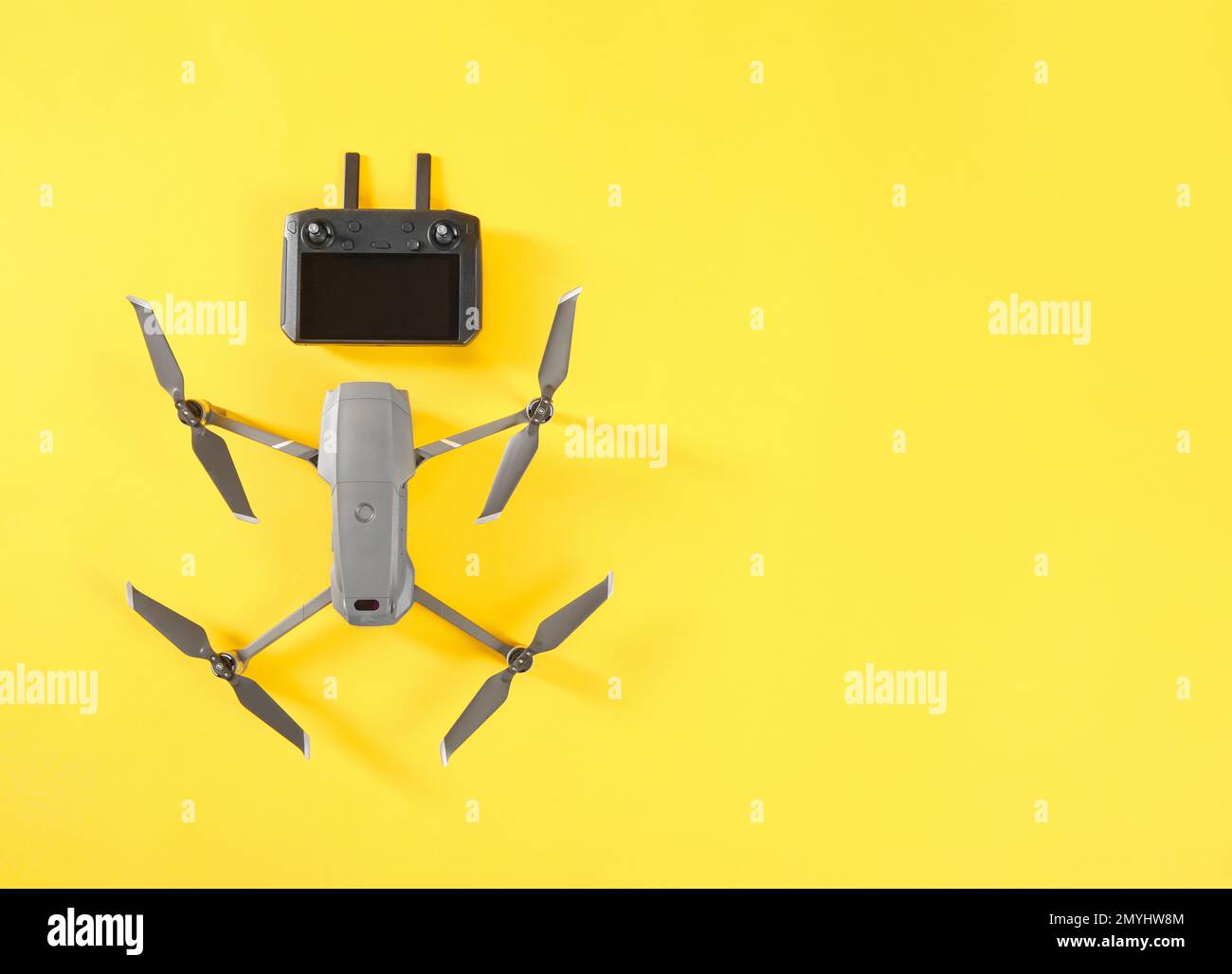 Drone and controller on yellow background, flat lay. Space for text ...