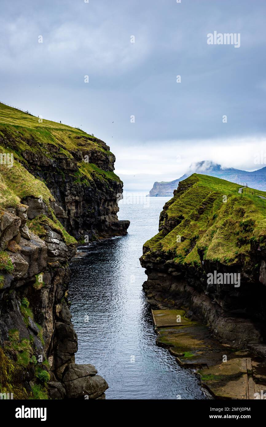 The narrow slot canyon harbor of Gjogv sandwiched between two cliffs on ...