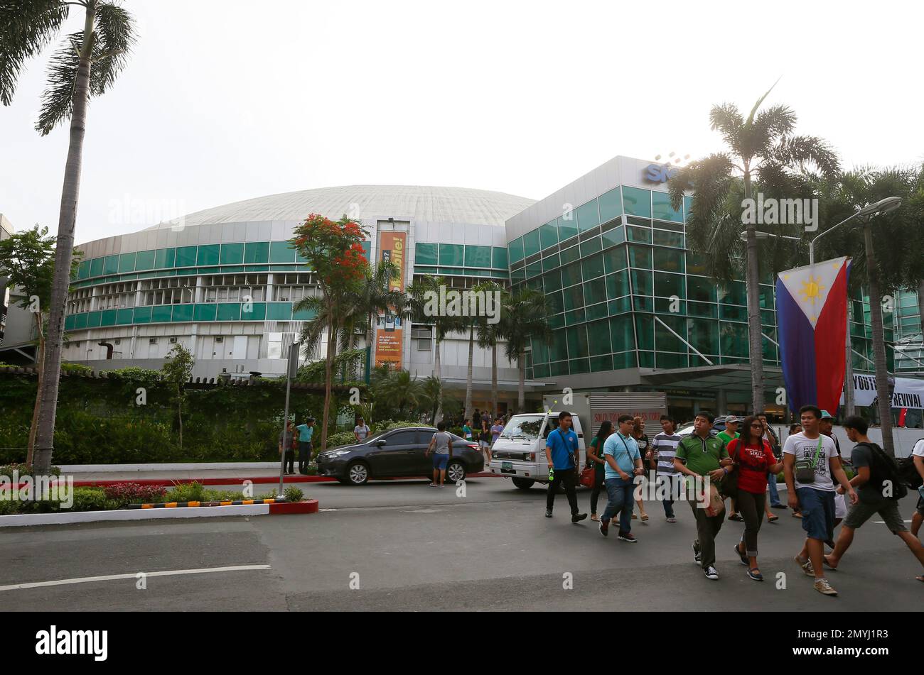 People cross the street with the Smart Araneta Coliseum in the ...
