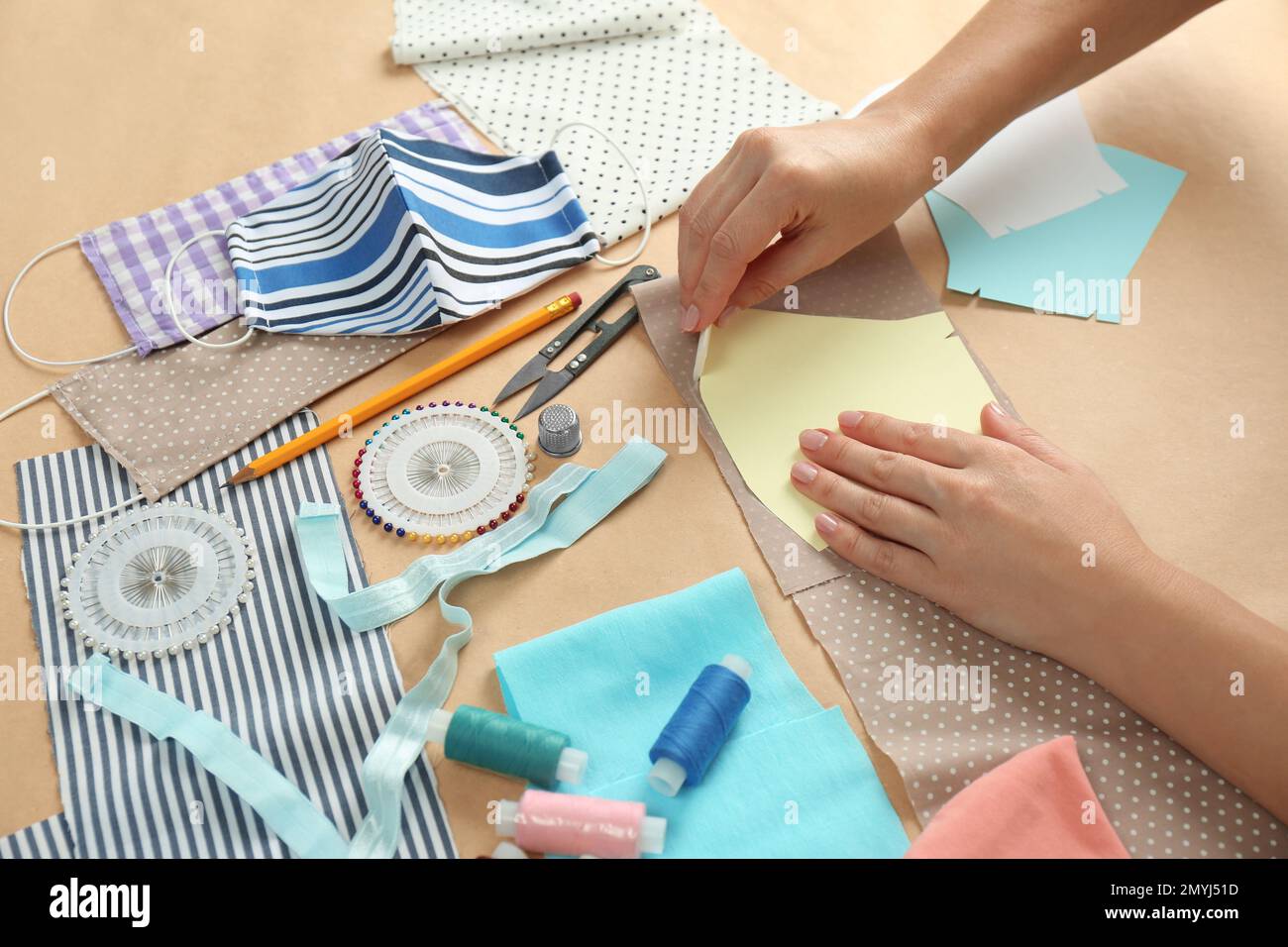 Woman making sewing template for cloth mask at table, closeup. Personal ...