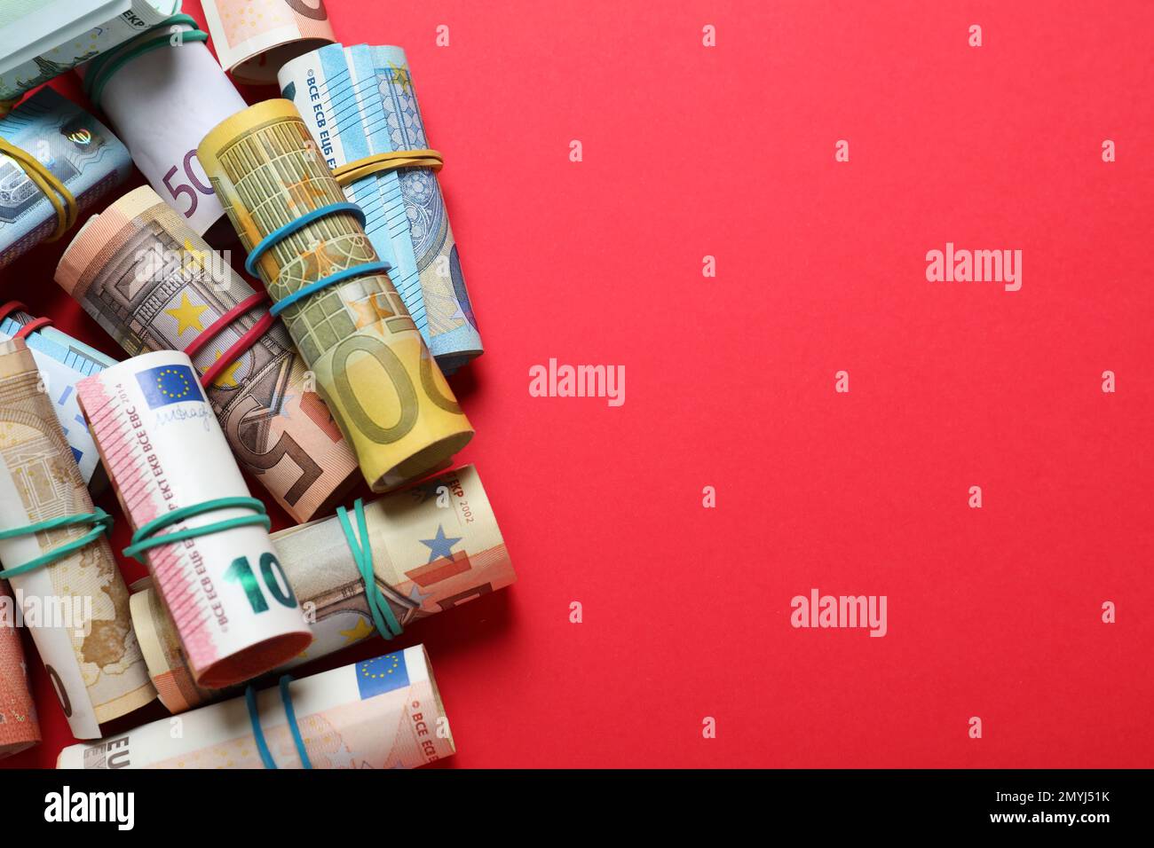 Rolled money with rubber band on red background, flat lay. Space for ...